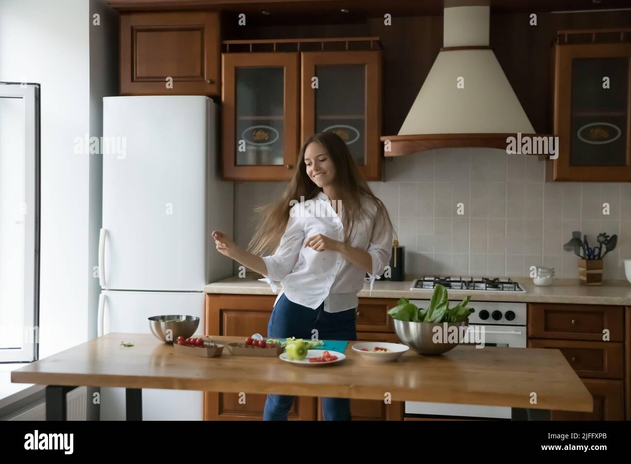 Millennial single woman dance in kitchen while cooking dinner Stock ...