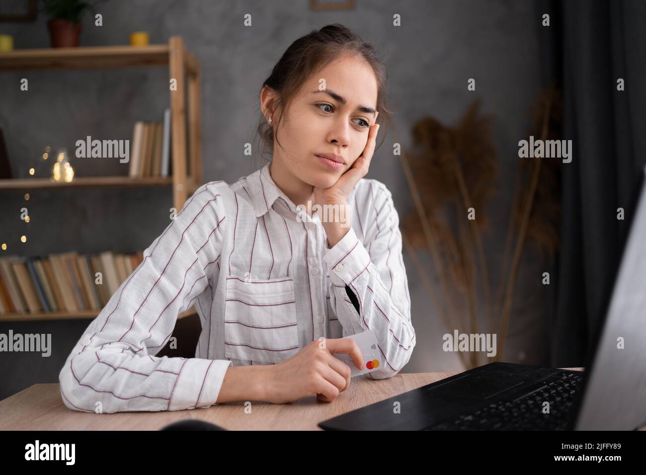 Bored young girl sit at home office table look and work at laptop ...