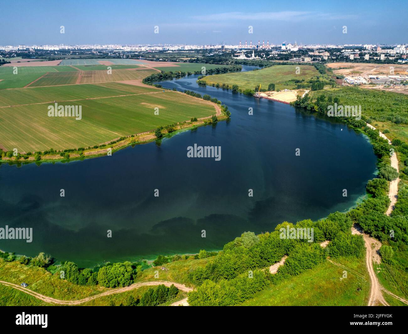 Wide river flowing between fields Stock Photo - Alamy
