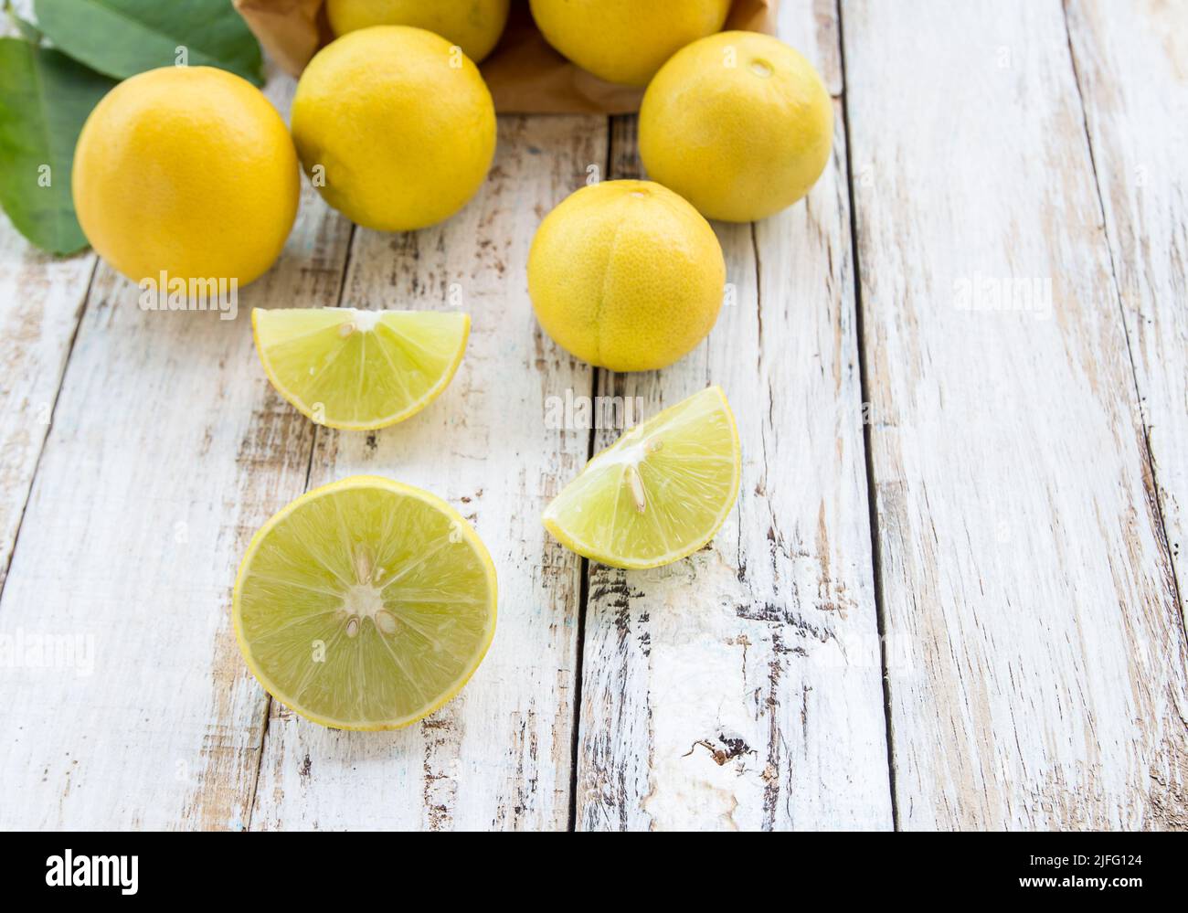 Freshly cut half and whole lemons on white wooden table background ...