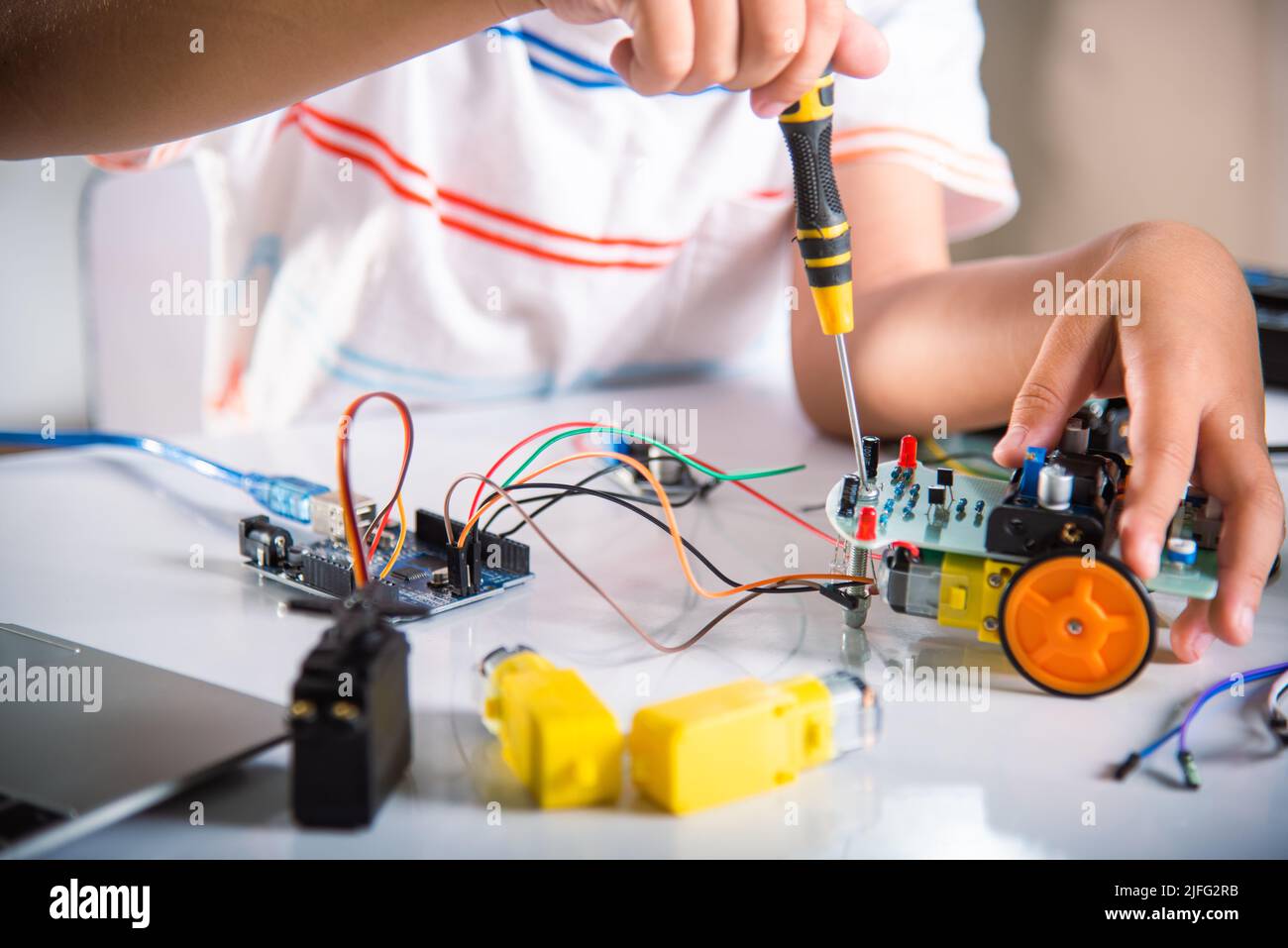 Little child tighten the nut with a screwdriver to assemble car toy ...