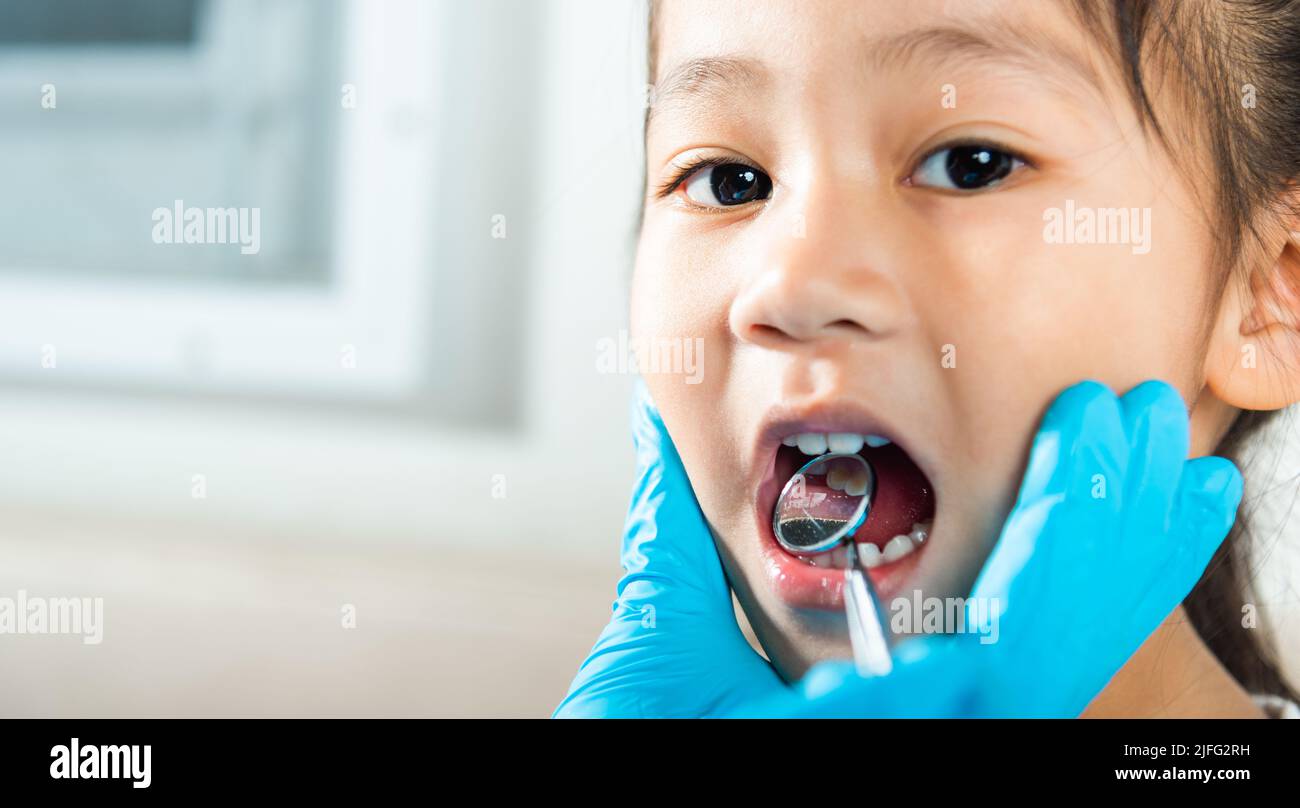 Dental kid health examination. Asian dentist making examination procedure for cute little girl ...