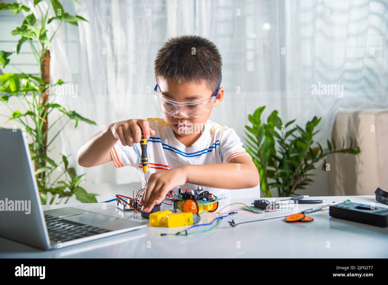 Little child tighten the nut with a screwdriver to assemble car toy ...