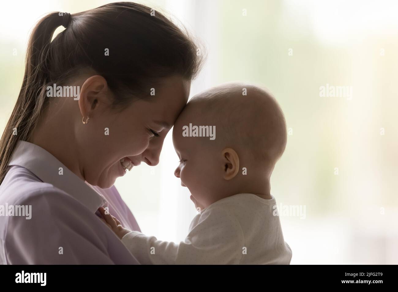 Cute baby and young laughing mother touch foreheads, close up Stock ...