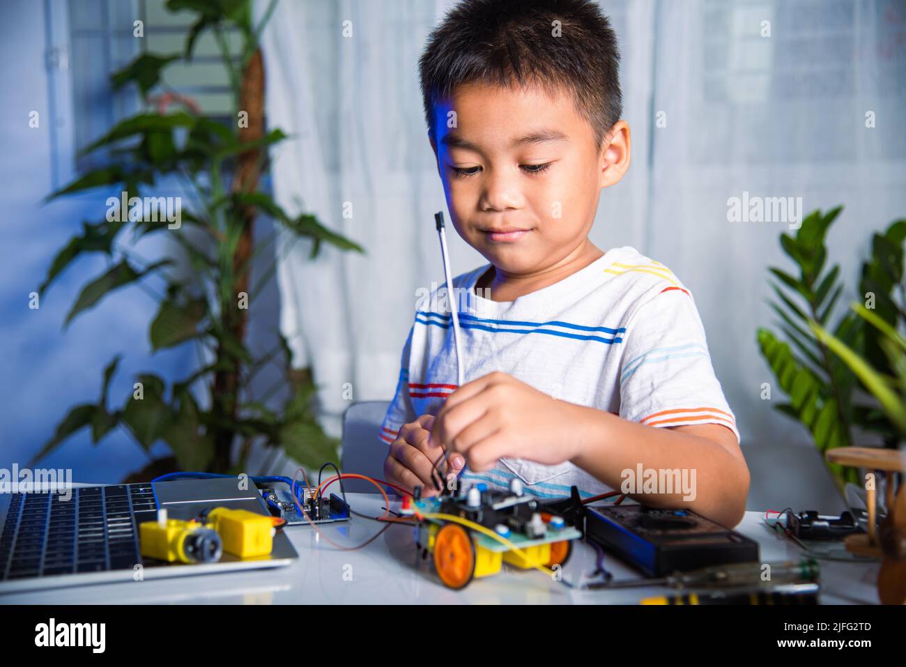 Asian kid boy plugging energy and signal cable to sensor chip with ...