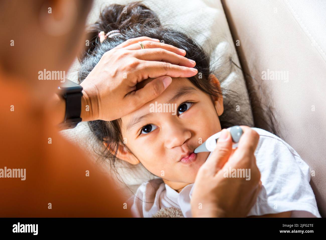 Sick kid. Mother parent checking temperature of her sick daughter with digital thermometer in ...