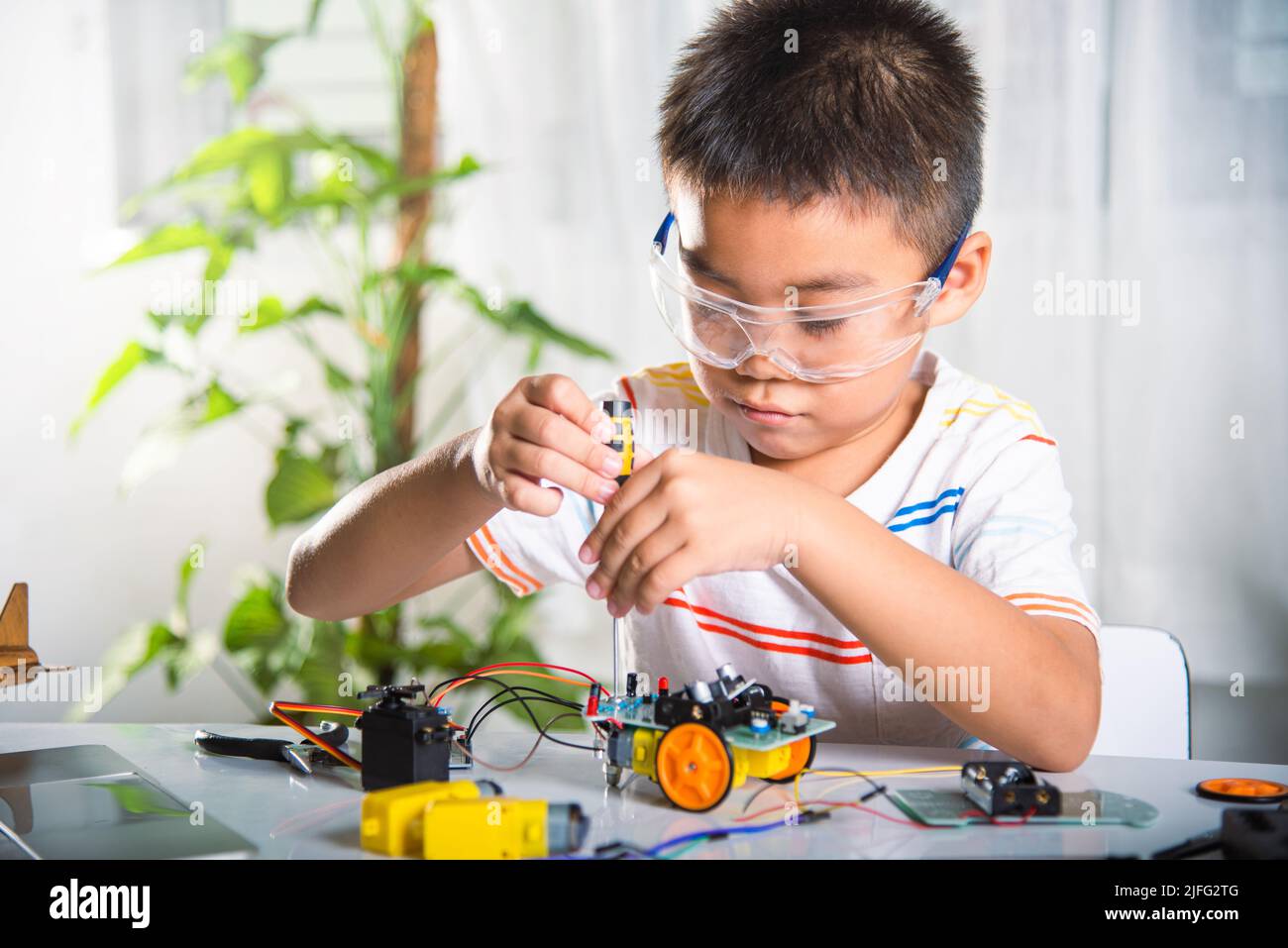 Little child tighten the nut with a screwdriver to assemble car toy ...