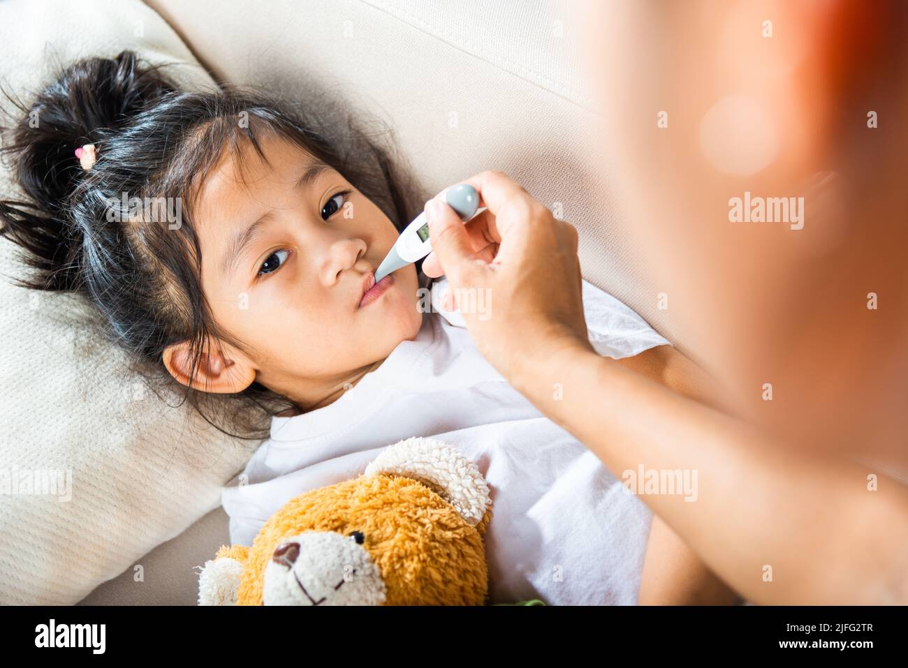 Sick kid. Mother parent checking temperature of her sick daughter with digital thermometer in ...