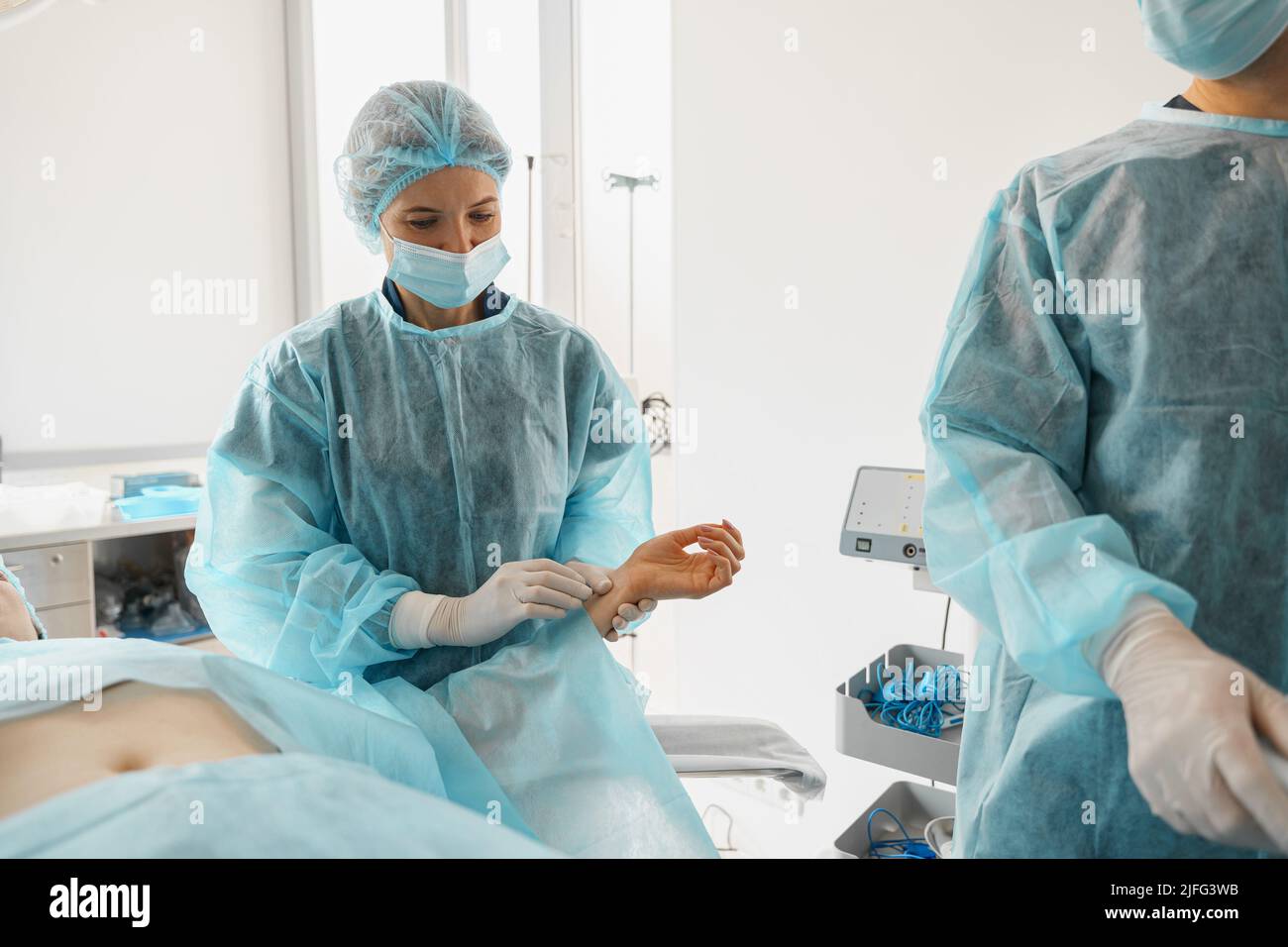 Doctor surgeon checking patient pulse during surgery in operation room ...