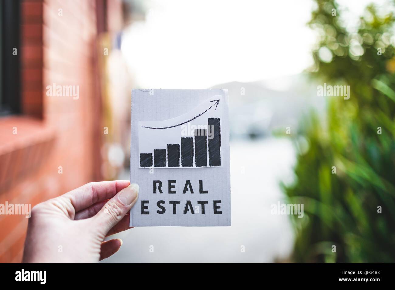 hand holding real estate sign with graph showing stats going up in ...