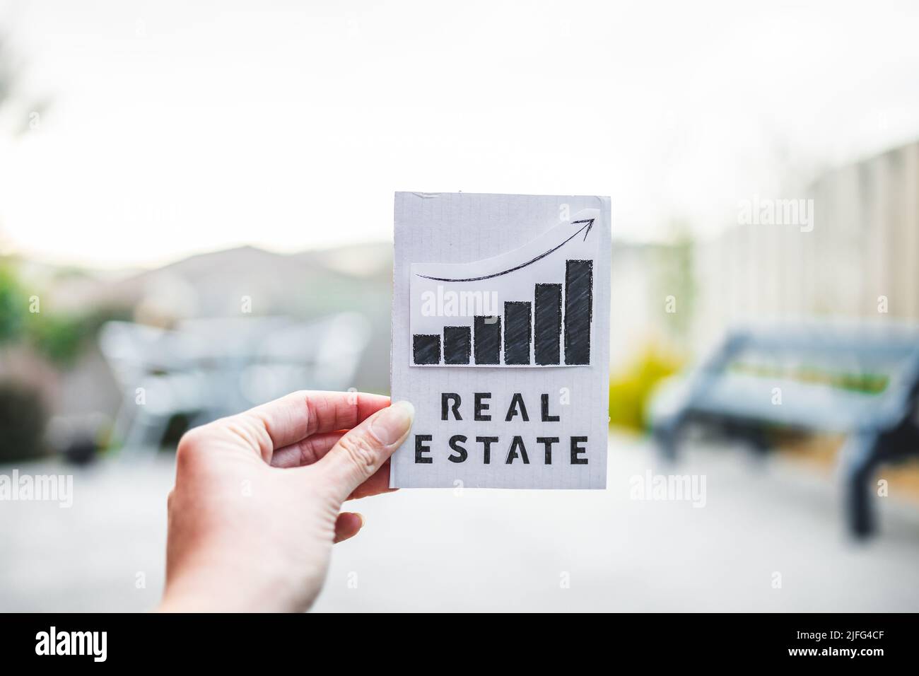 hand holding real estate sign with graph showing stats going up in ...