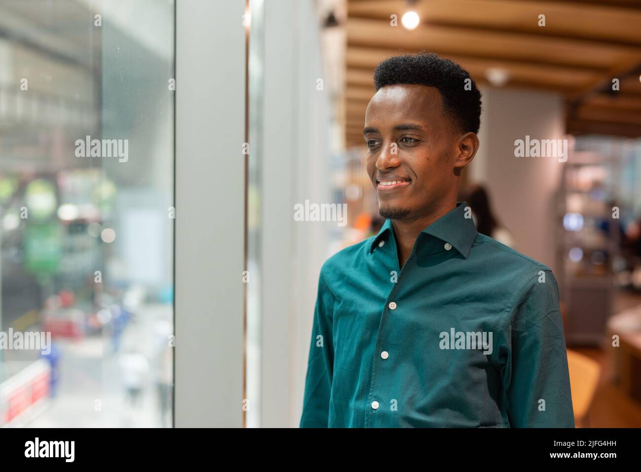 Portrait of handsome young black man in coffee shop looking through ...