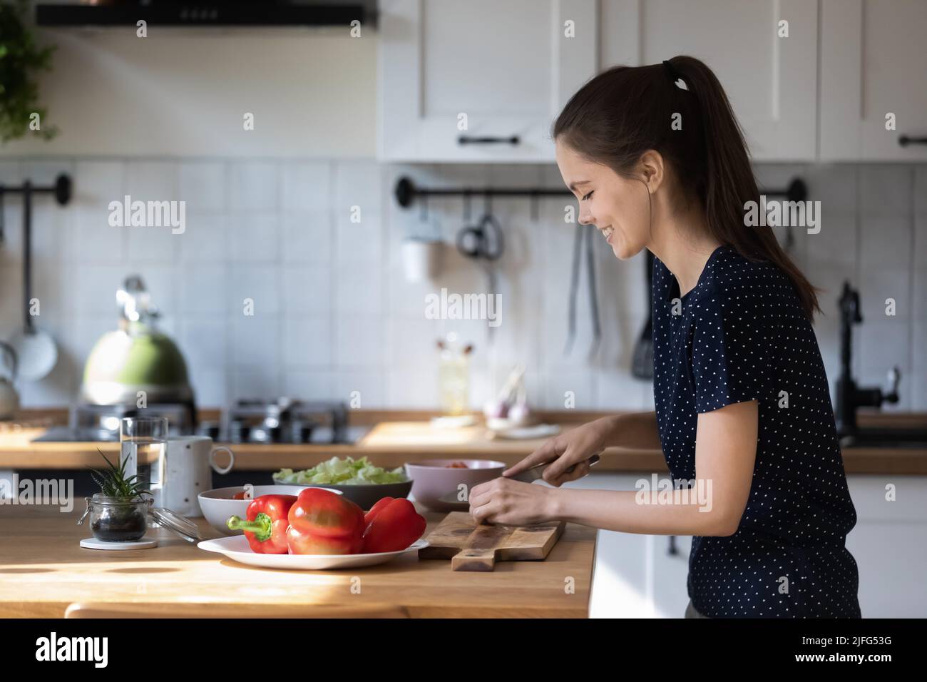 Happy positive chef blogger girl enjoying cooking, preparing salad ...