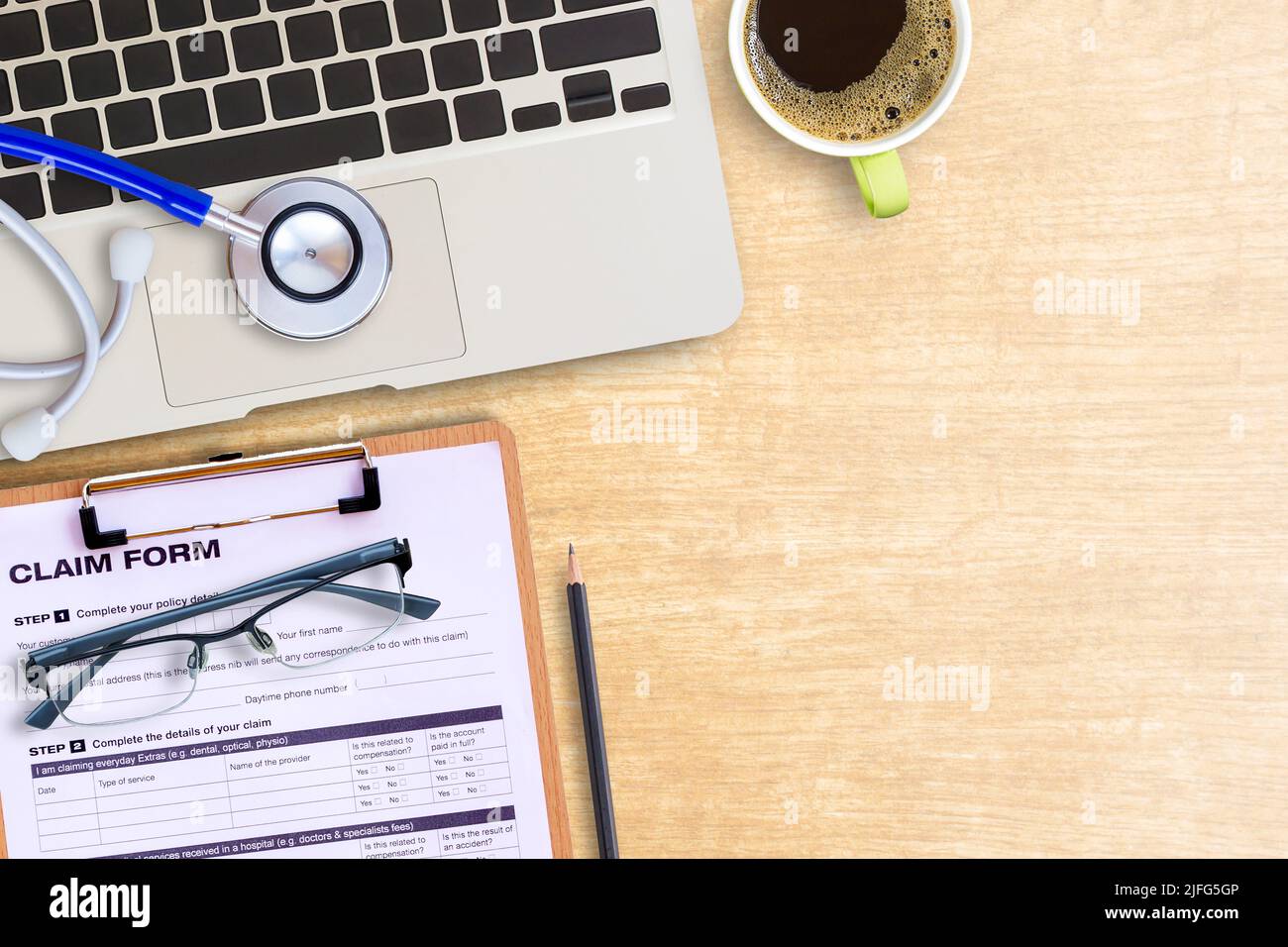 Laptop computer,medical claim form and glasses, pencil with cup of ...