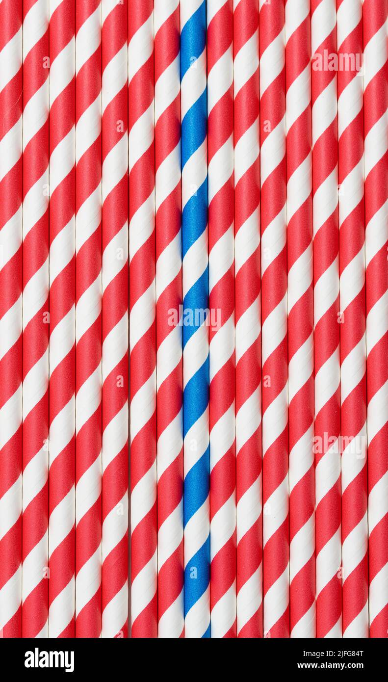 Full frame photo of red and white straws from above, one blue straw is ...