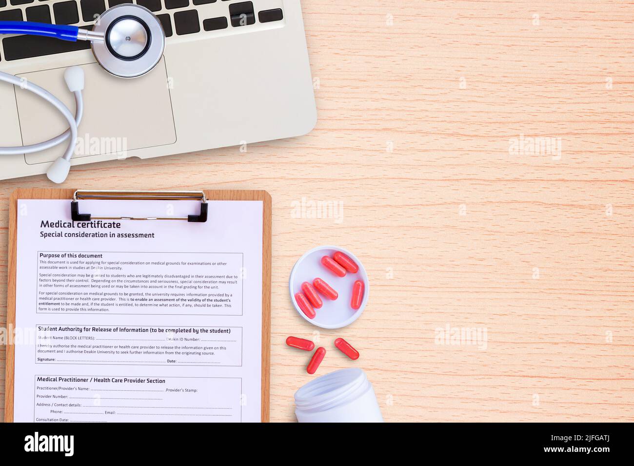 Laptop computer and pill with blue stethoscope on wooden desk. Top view ...