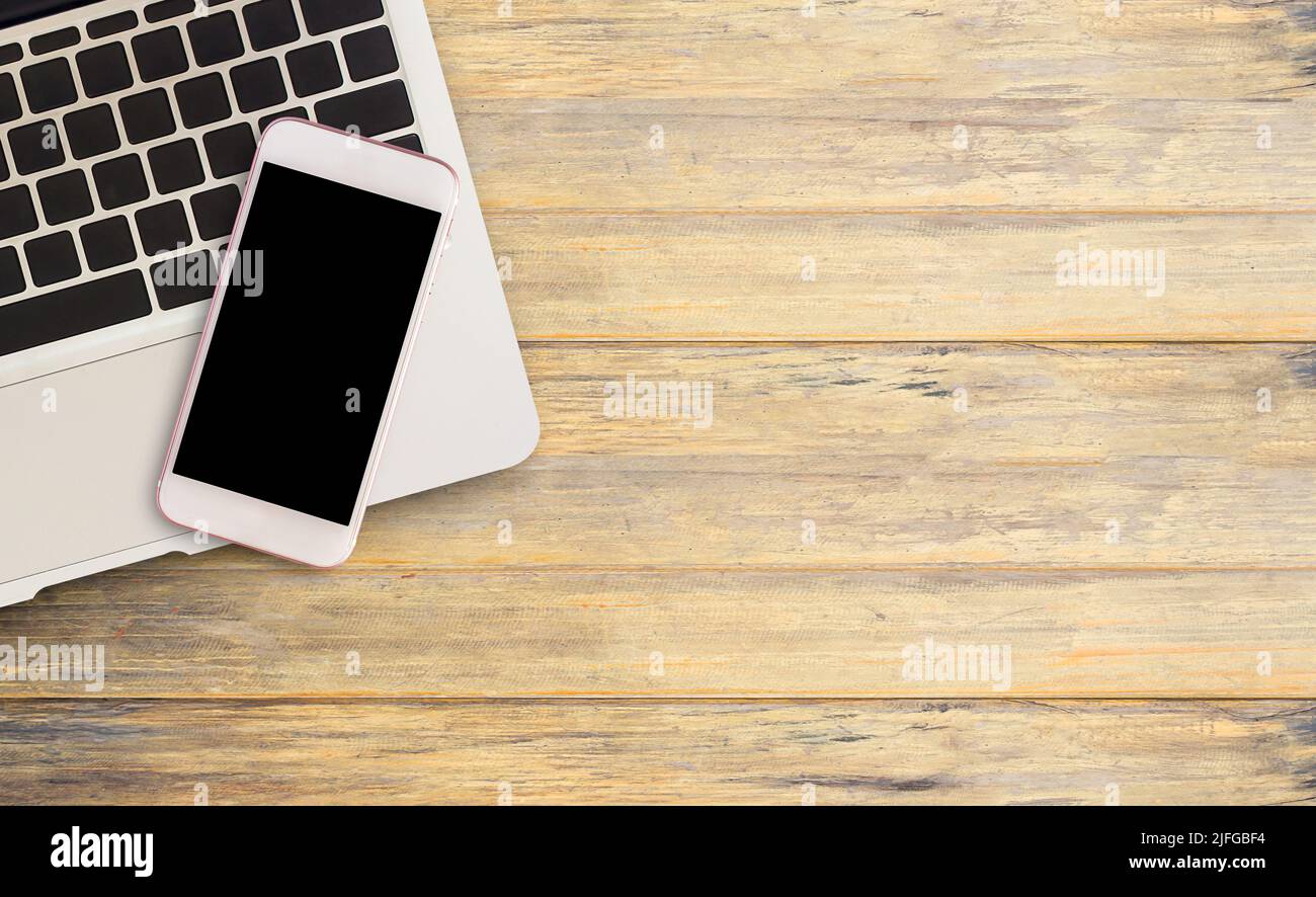 Smart phone and laptop computer on office desk or wood table. Top view ...