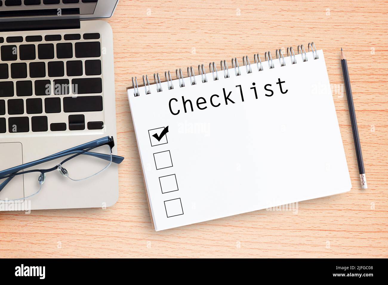 Laptop computer, glasses and notebook with words Checklist on office ...