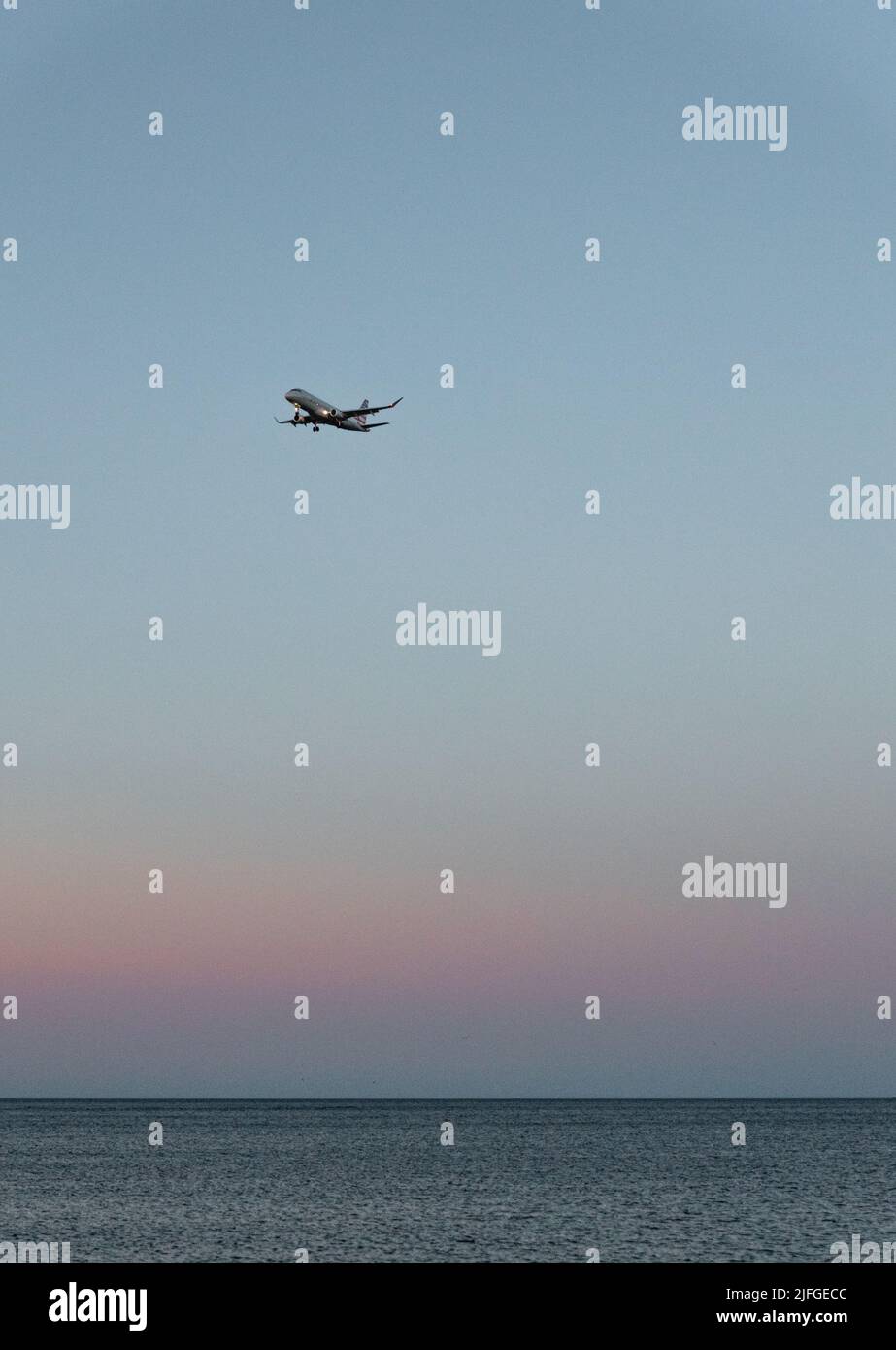 A vertical shot of a plane in flight over a sea in the evening Stock ...