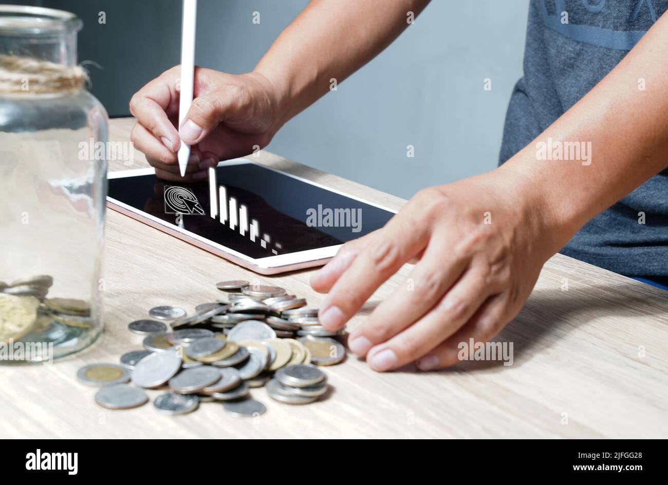 A male investor is using a valuation tablet with coins piled up on a ...