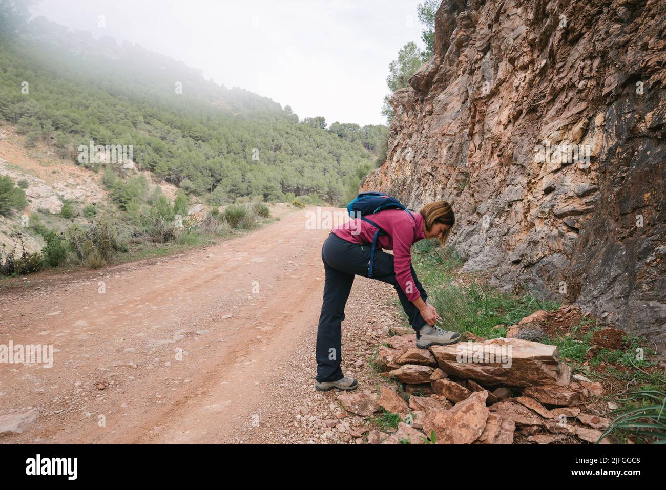 Female hiker tying her boot laces near the track Stock Photo - Alamy