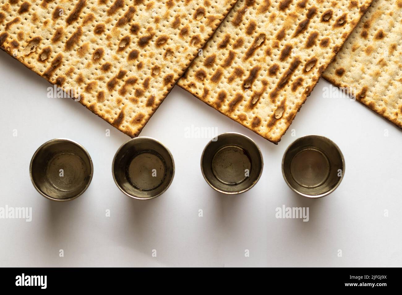 Three matzah bread - Jewish food for Passover. Next to four silver cups ...