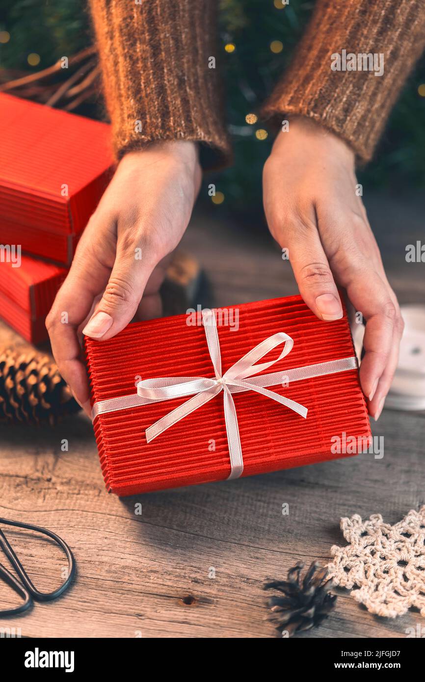 Female hands decorating the red Christmas gift box with the white ...