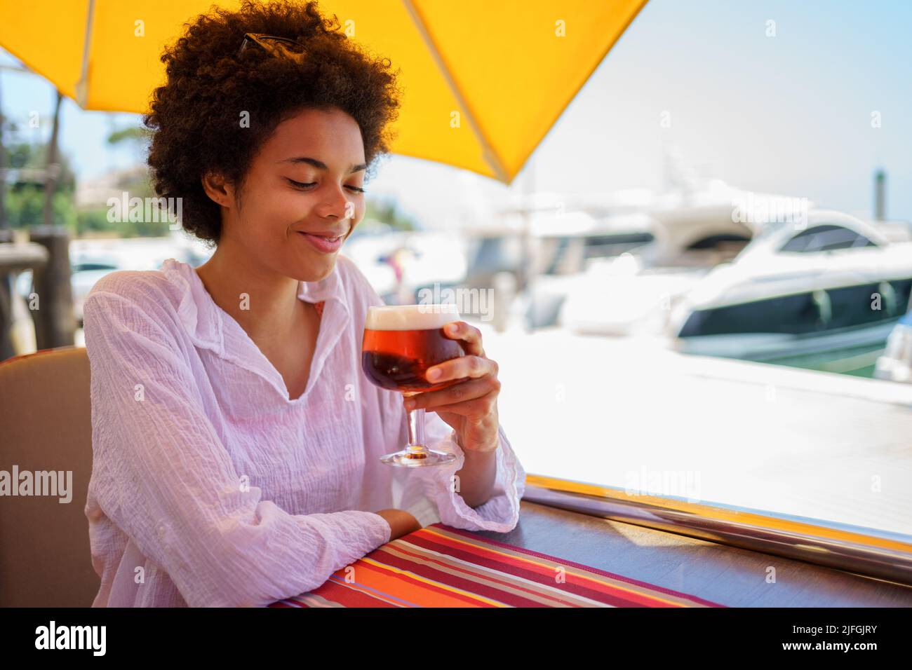 Young black female drinking beer in street restaurant Stock Photo - Alamy