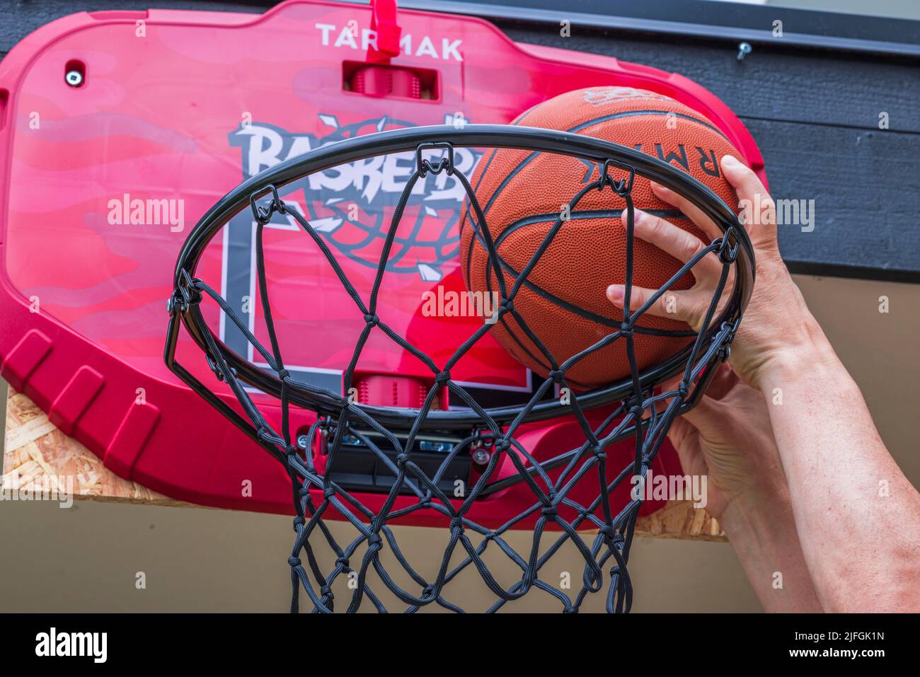 Close up view of man scoring ball into basketball hoop with net while ...
