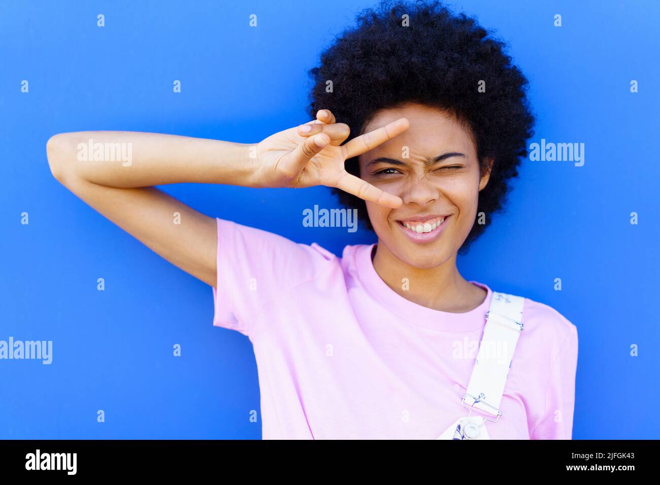 Cheerful black woman making peace sign near wall Stock Photo - Alamy