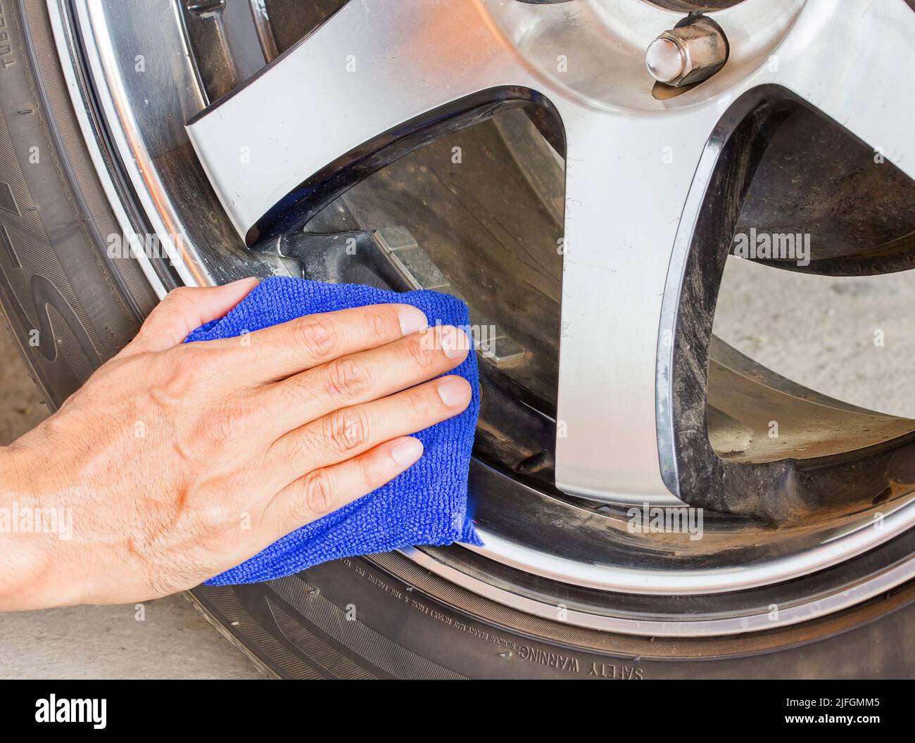 Hand with microfiber cloth cleaning wheel car Stock Photo - Alamy