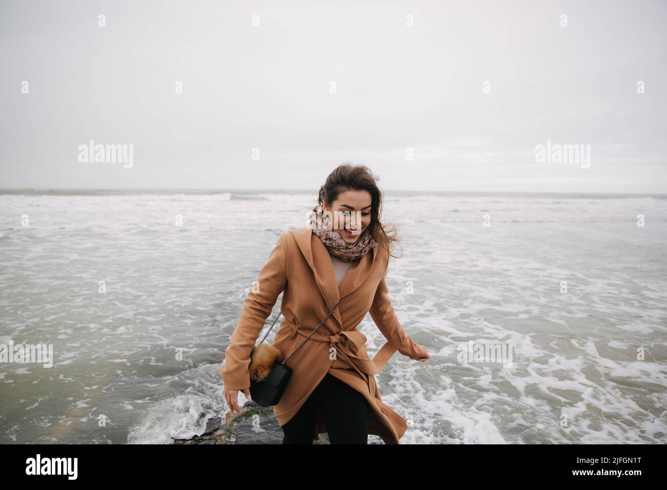 Woman running away from the waves of North Sea. Female afraid to be wet ...