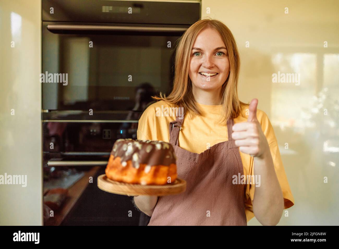 Smiling young 30s woman chef cook in apron standing at the kitchen ...