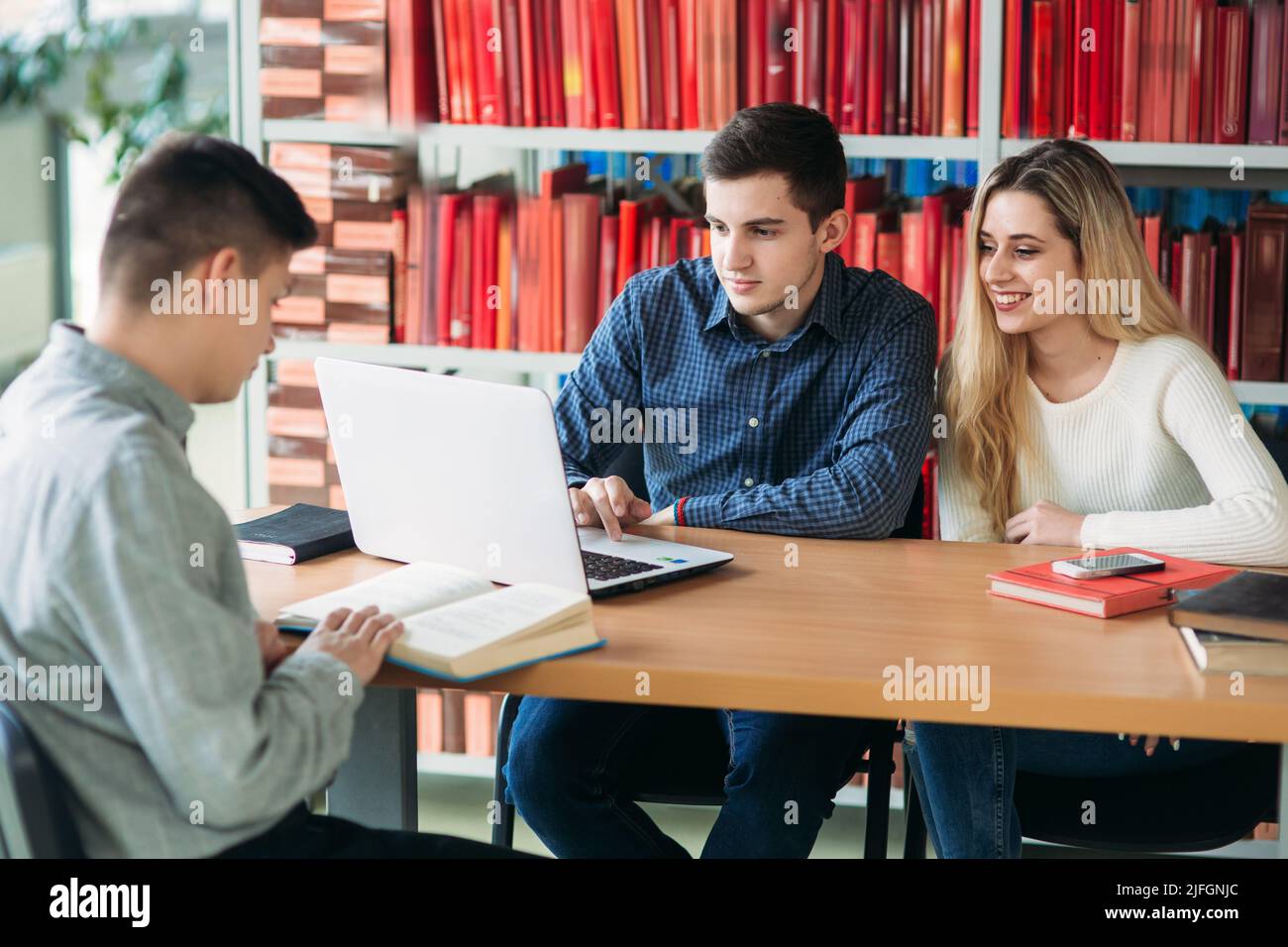 University students sitting together at table with books and laptop ...