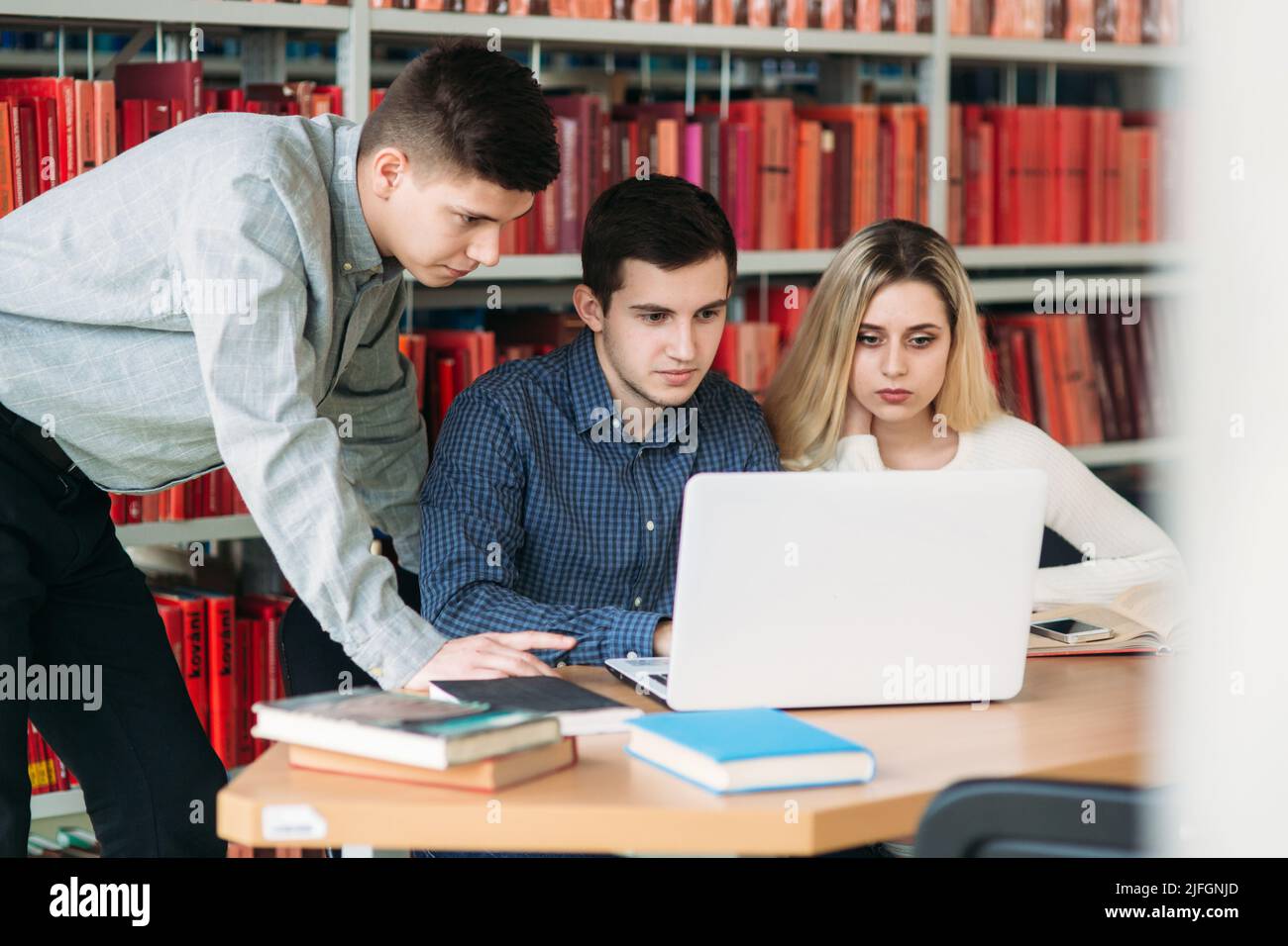 University students sitting together at table with books and laptop ...