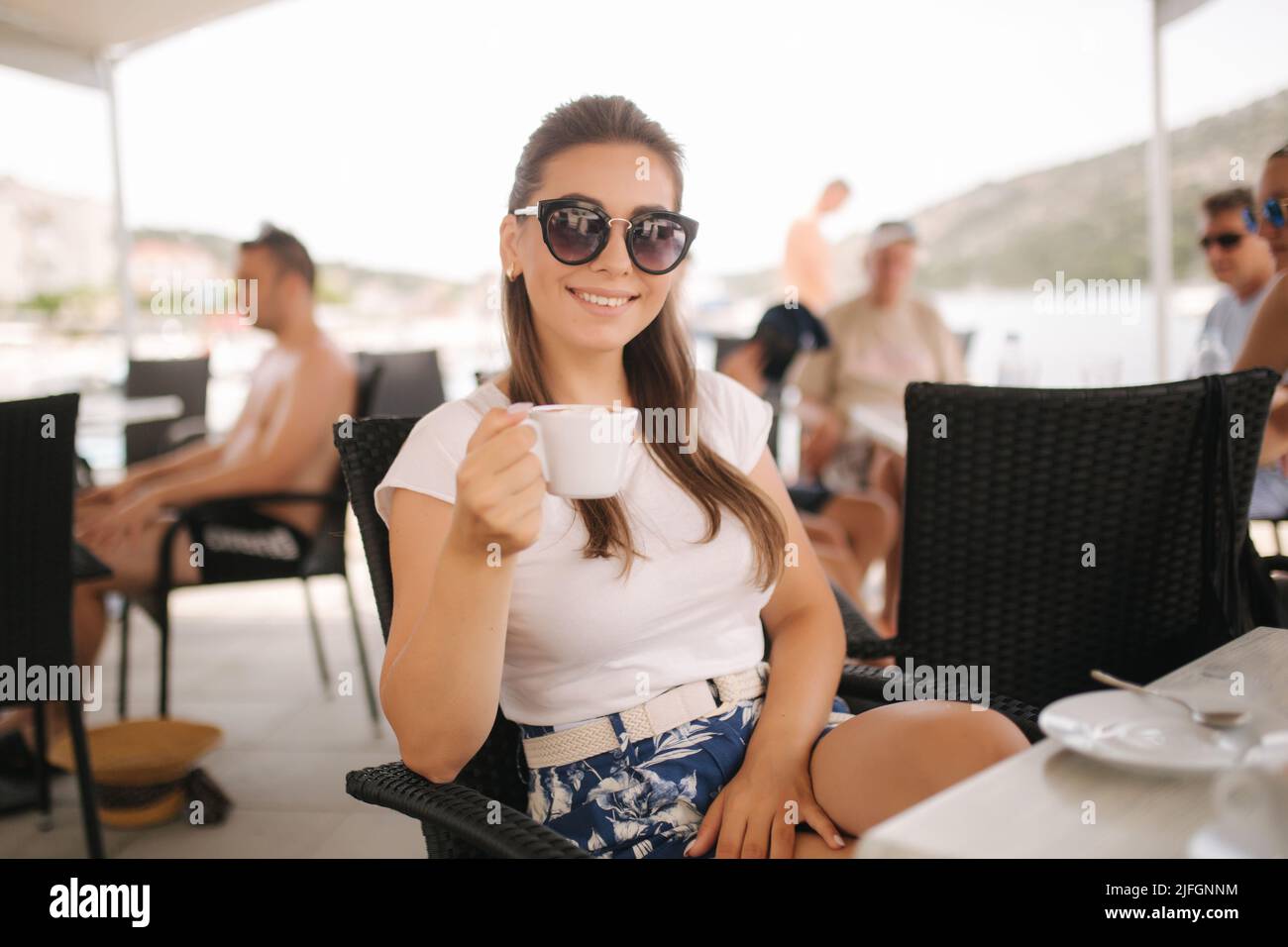 Beautiful woman drink coffe in cafe outside. Background of sea Stock ...