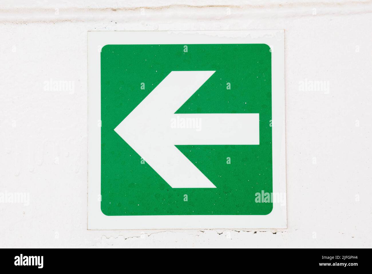 Green arrow escape sign pointing to the left Stock Photo - Alamy