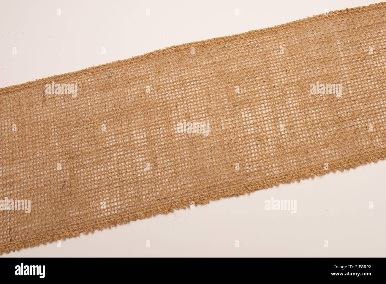 A closeup of a hessian jute cloth laid diagonal isolated on white ...