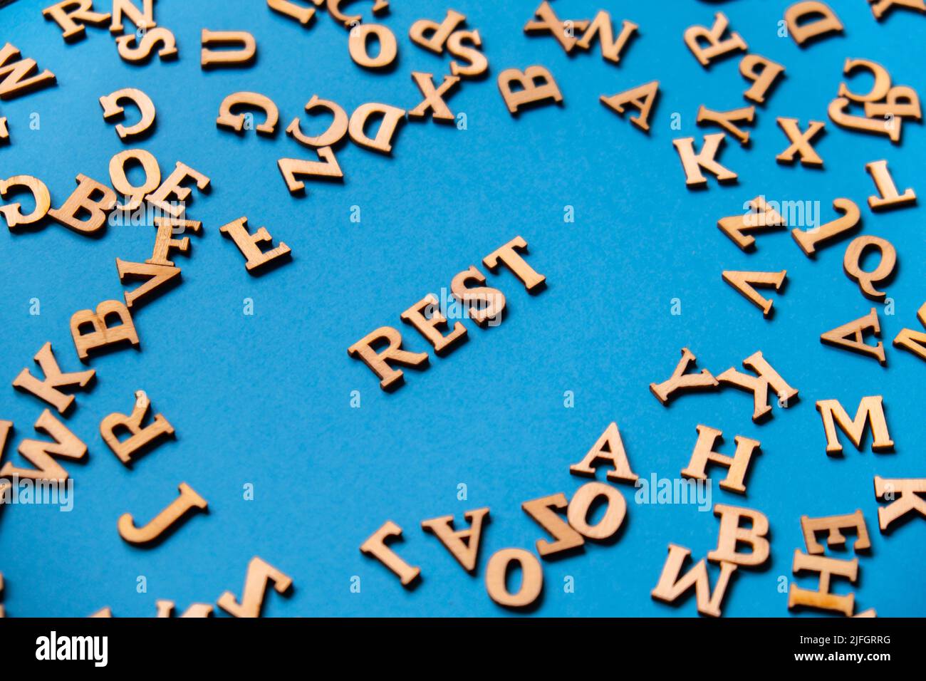 Word REST made out of wooden letters on bright blue background ...
