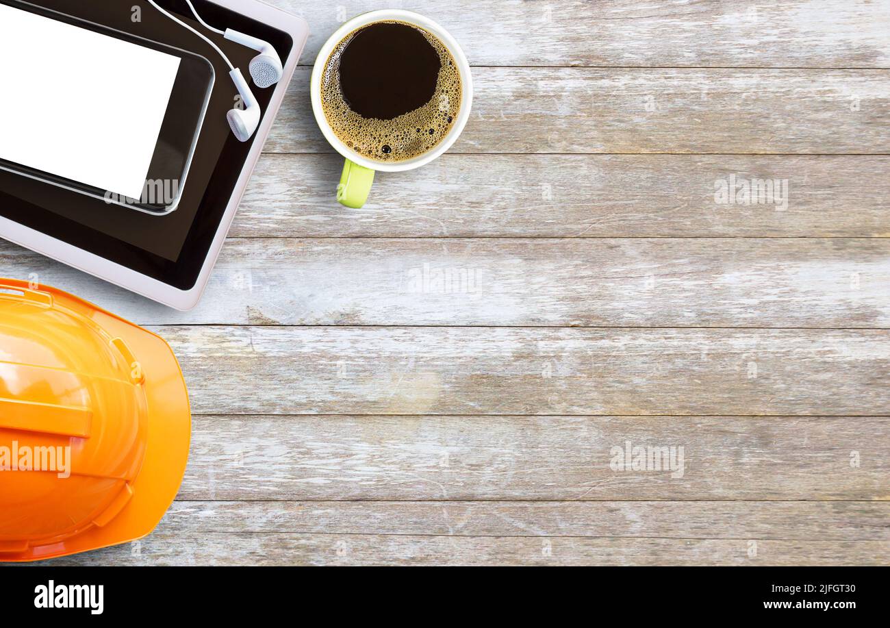 Office desk-Black coffee in a green cup,safety helmet and smart phone ...