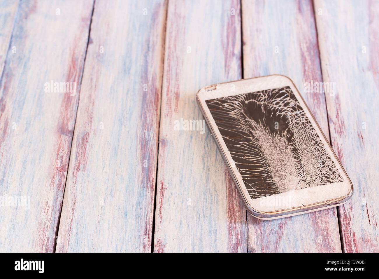 Mobile smartphone with broken screen on wooden table or office desk ...