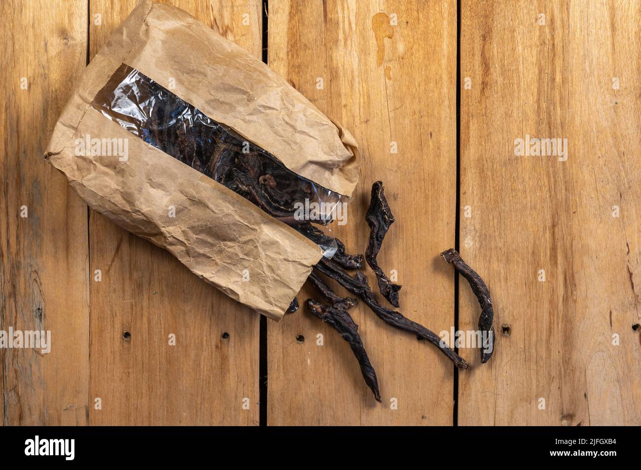 Sticks of dried meat against a wooden background. Pieces of dried beef ...