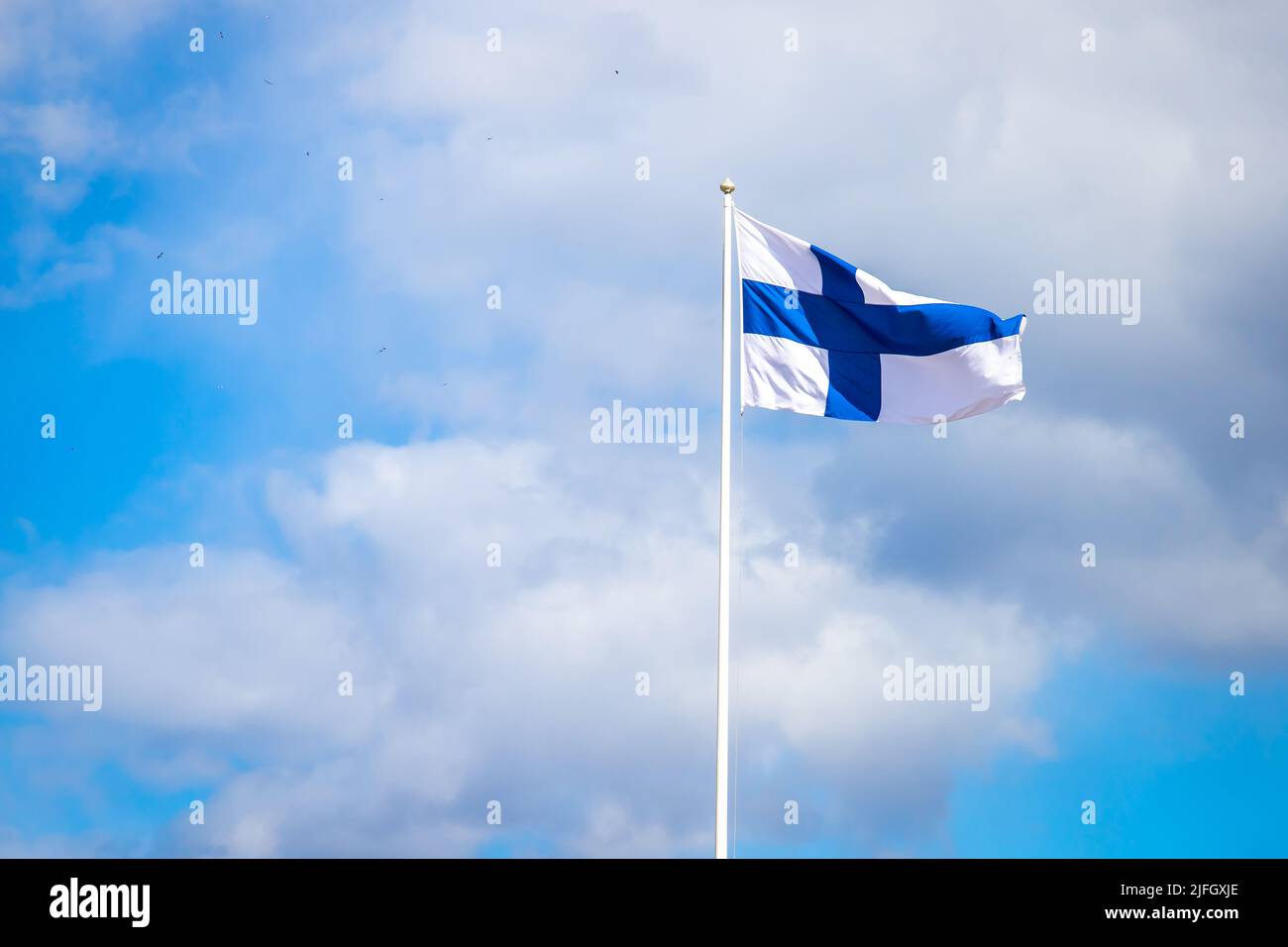 A Finland flag waving on a flag pole in background of cloudy sky Stock ...