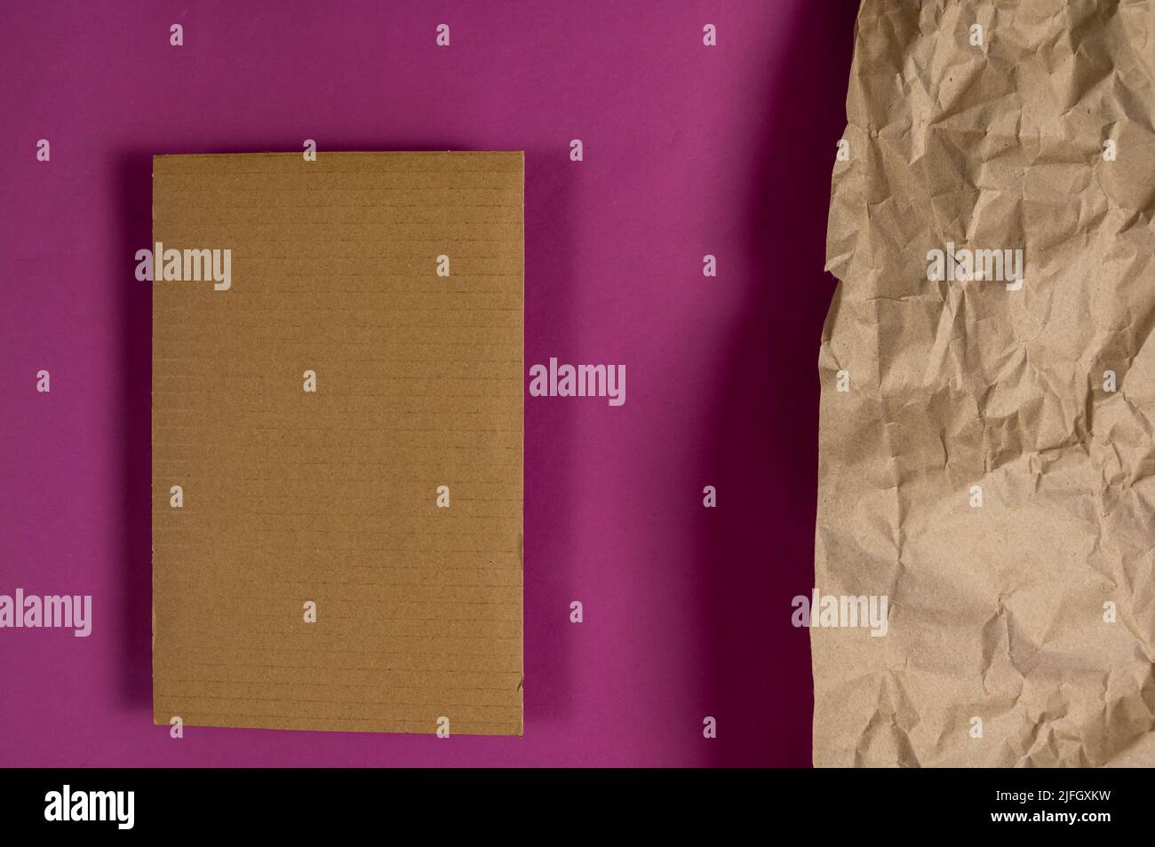 Rectangular piece of brown cardboard on magenta. Crumpled wrapping ...