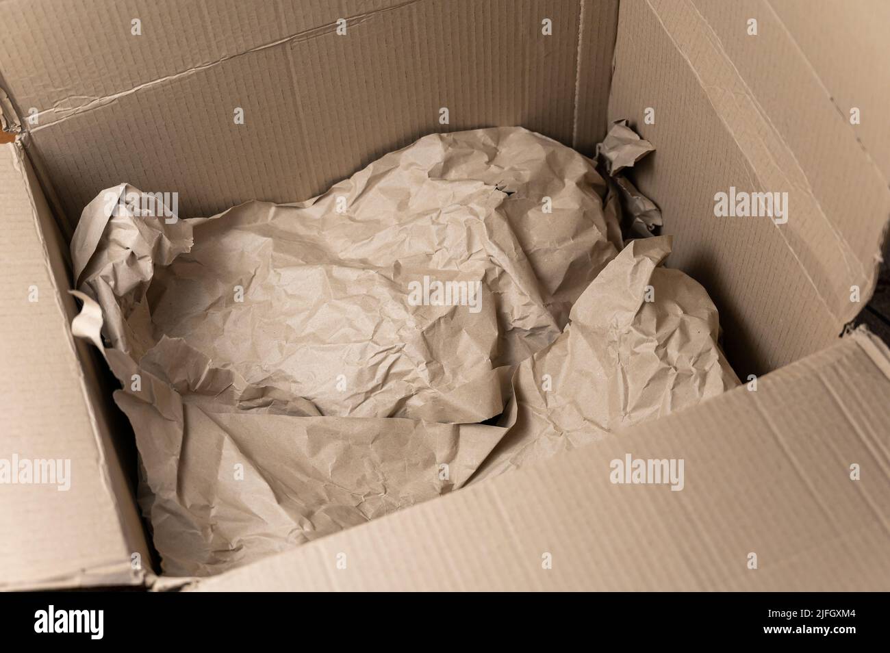 Open cardboard box. Crumpled wrapping paper inside the box. Top view ...