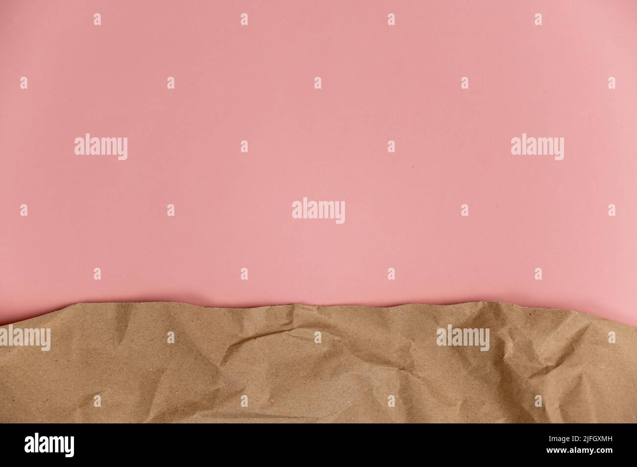 Wrapping paper against a pink background. Crumpled sheet of light brown ...