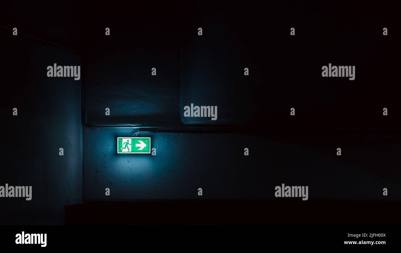 A closeup of a neon emergency exit sign in an underground garage Stock ...
