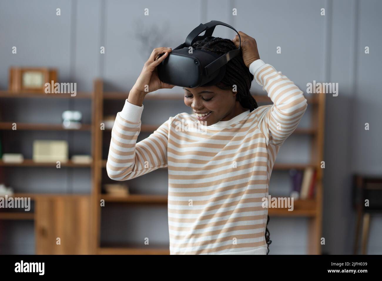 Inspired afro woman at home put on vr helmet to enjoy virtual reality online game cyber ...
