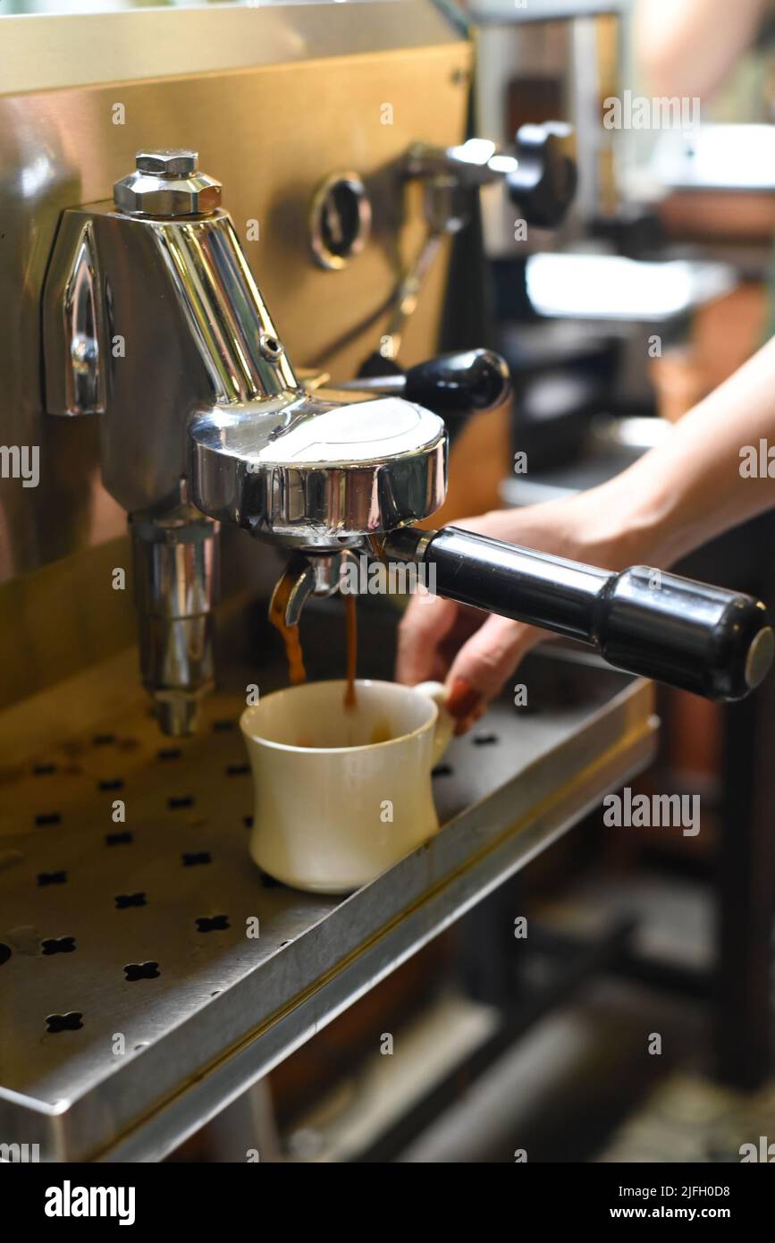 Woman's hand holding a cup while making coffee with a coffee machine ...