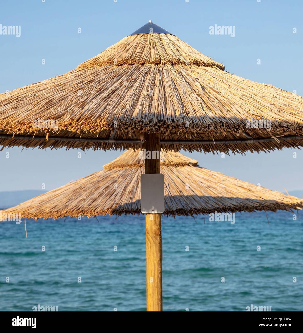 Straw beach umbrellas close up. Sunny day at sea. Blue sky and ocean ...